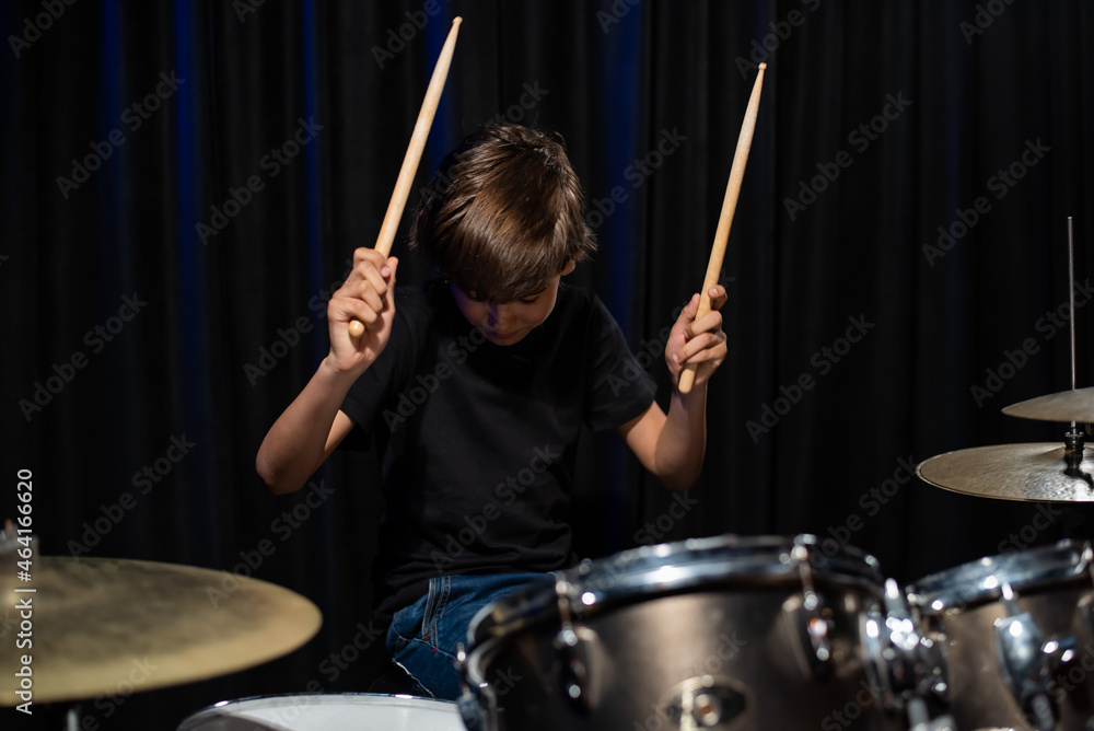 The boy learns to play the drums in the studio on a black background ...