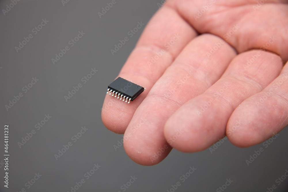 Hand holds chip compenent. Embedding the chip under human skin ...