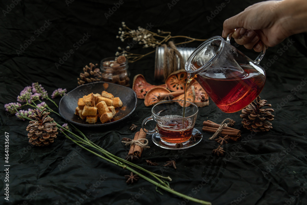 Bael fruit tea is poured from a kettle into glass cup with bark of bael ...
