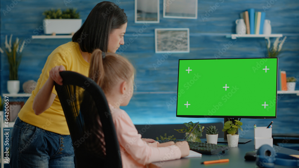 Mother and daughter looking at horizontal green screen on computer at ...