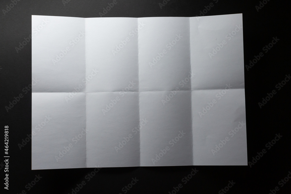 Light and shadow on creases in sheet of white paper folded into eight ...