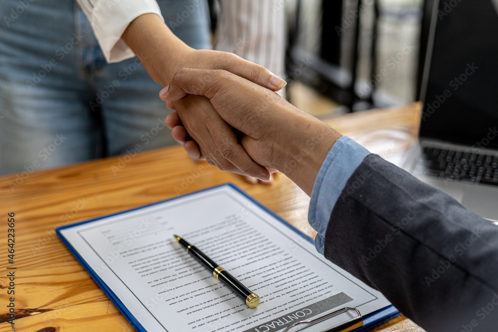 Foto de Two businesswomen shake hands after accepting a business ...