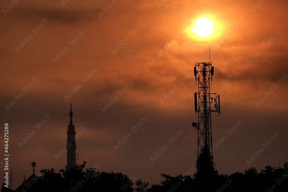 mosque minaret and communication tower during sunrise. radio frequency ...