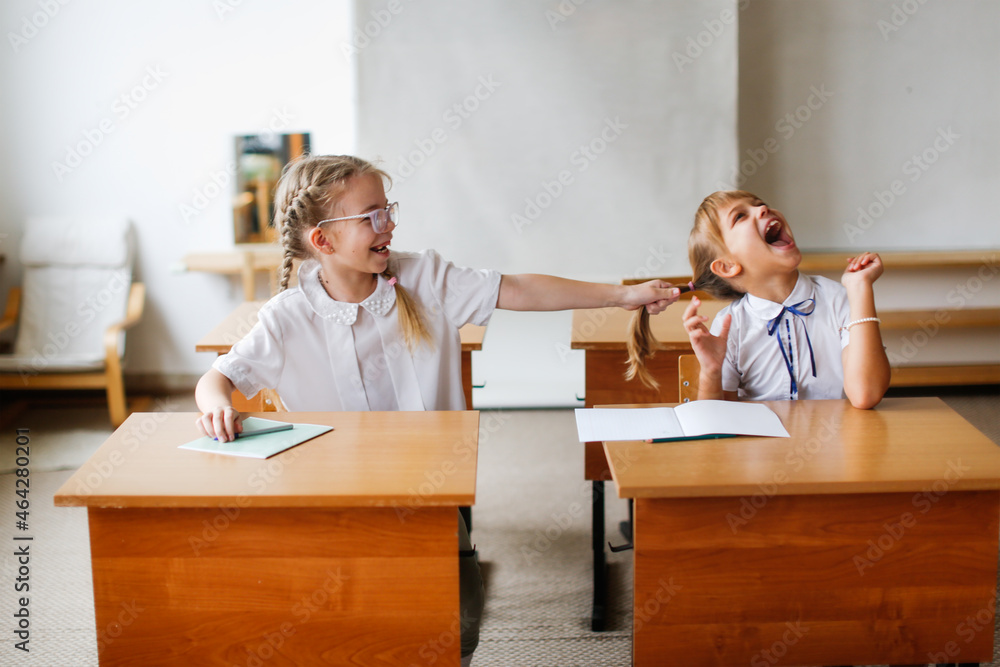 Two schoolchildren, children at their desks in a bright classroom, a ...