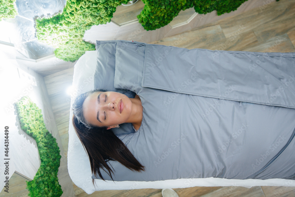 A young beautiful girl is doing a cosmetology procedure full body wrap ...