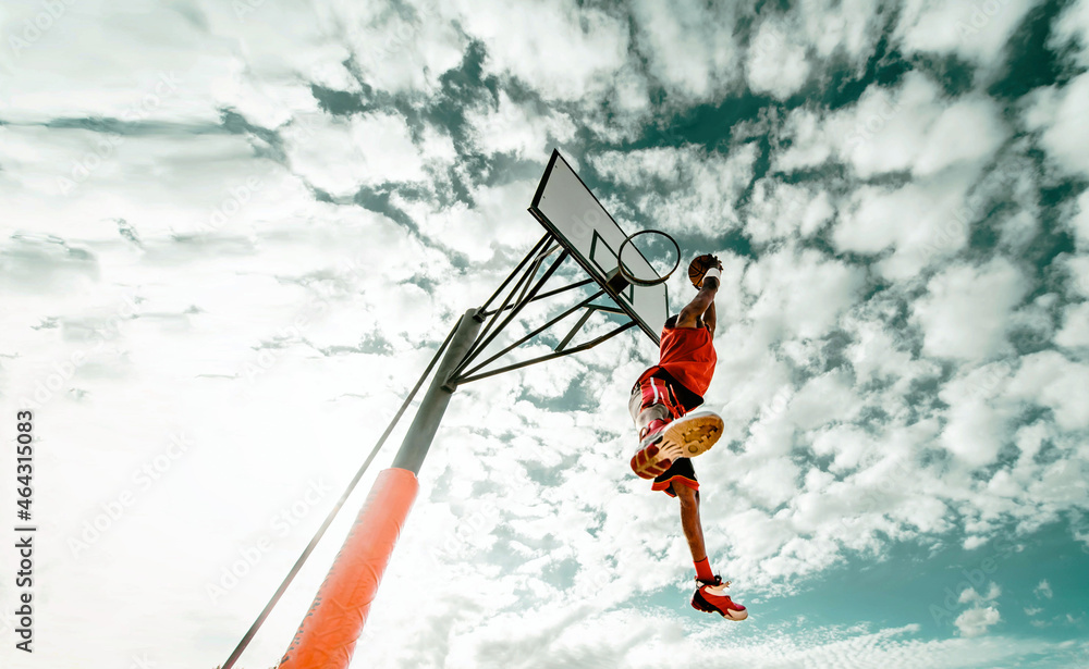 Street basketball player making a powerful slam dunk on the court ...