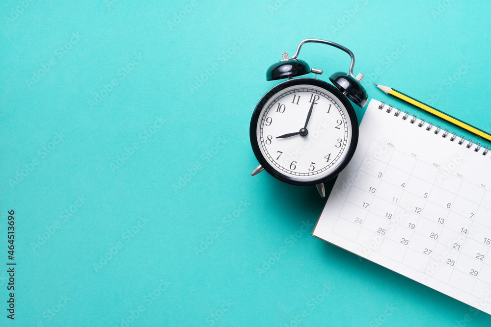 close up of calendar and alarm clock on the green table background ...