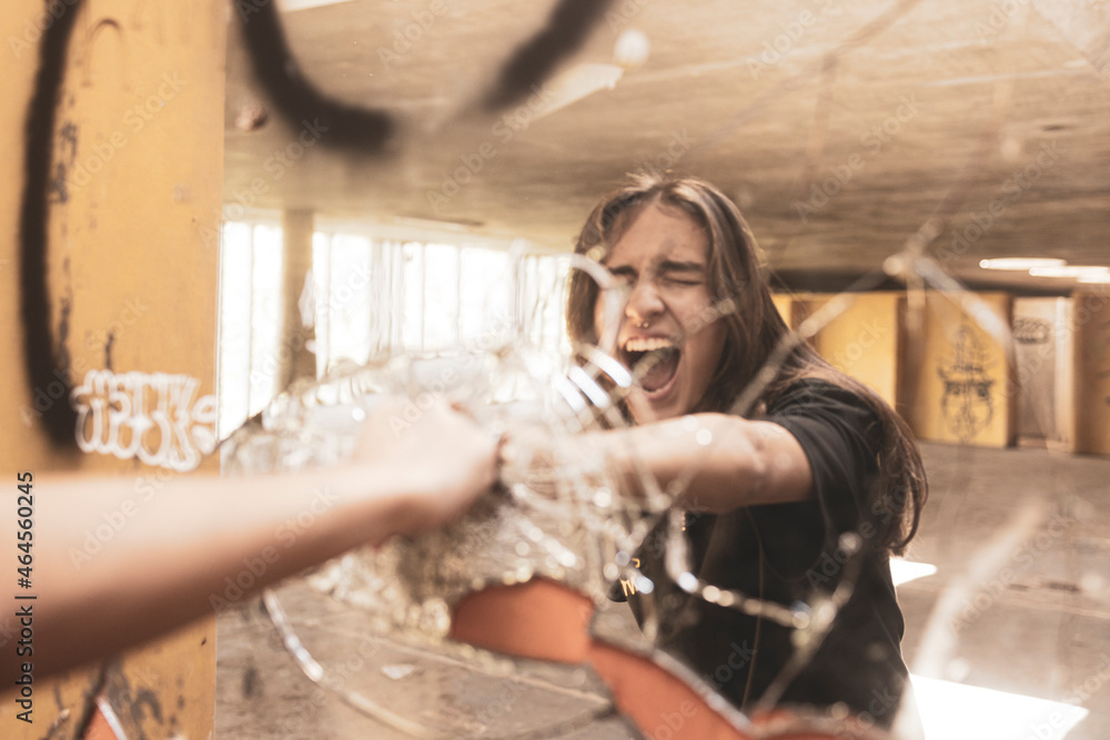 Young urban teenager girl punching and breaking a mirror in rage and ...