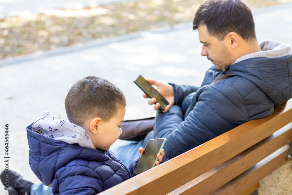 Foto Stock Addicted phone users.little boy sitting on the bench next to ...