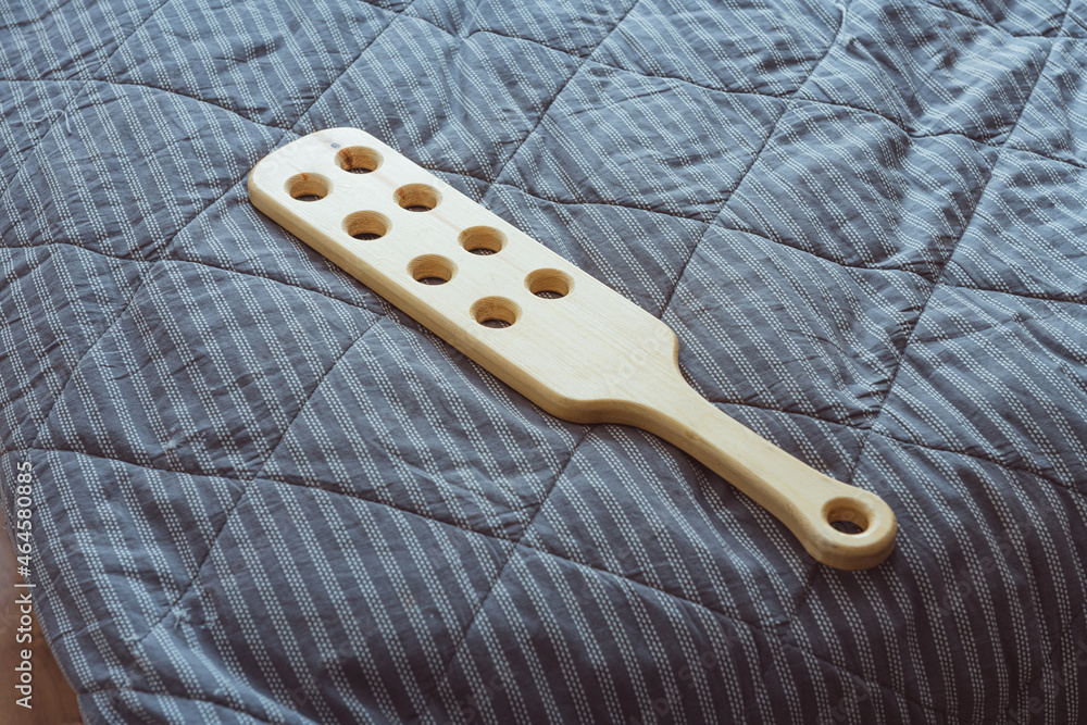 Wooden paddle on bed prepared for spanking. Domestic discipline ...