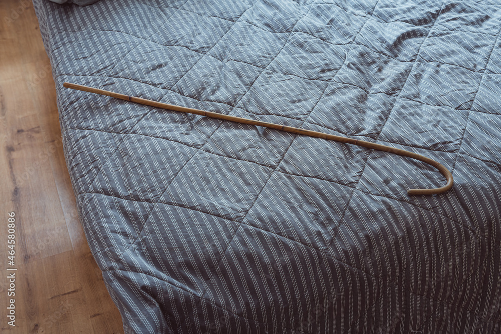 Rattan cane on bed prepared for spanking. Domestic discipline, spanking ...