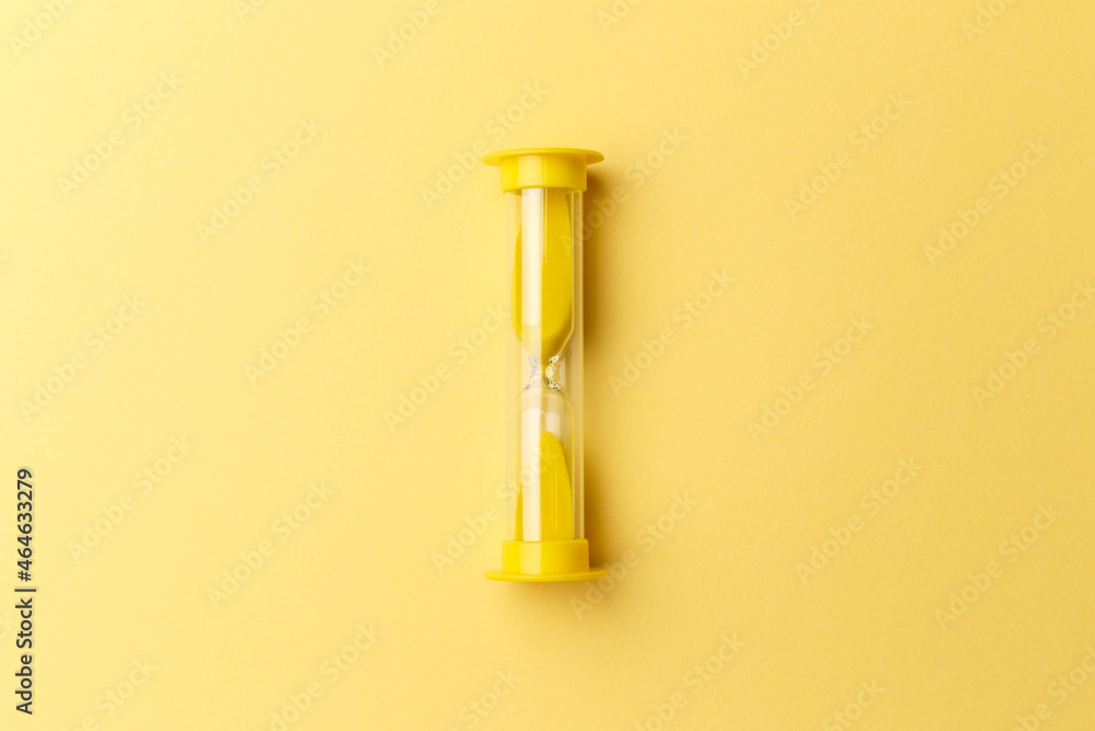 Modern yellow Hourglass with yellow background. Sand trickling through ...