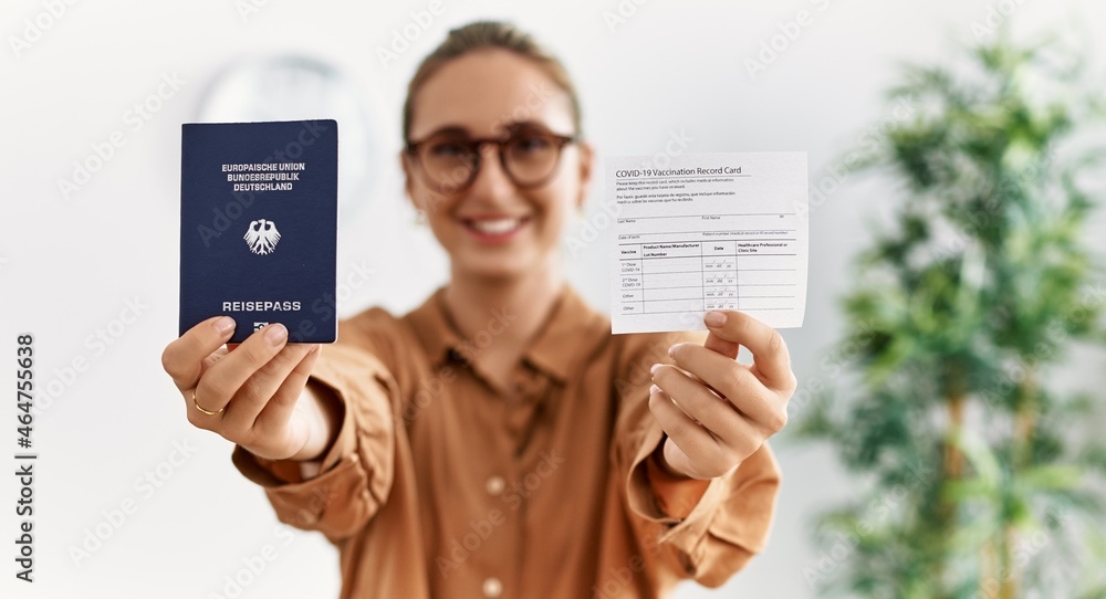 Young blonde woman holding covid vaccination record card and ...