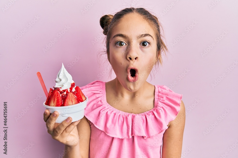 Beautiful brunette little girl eating strawberry ice cream scared and ...