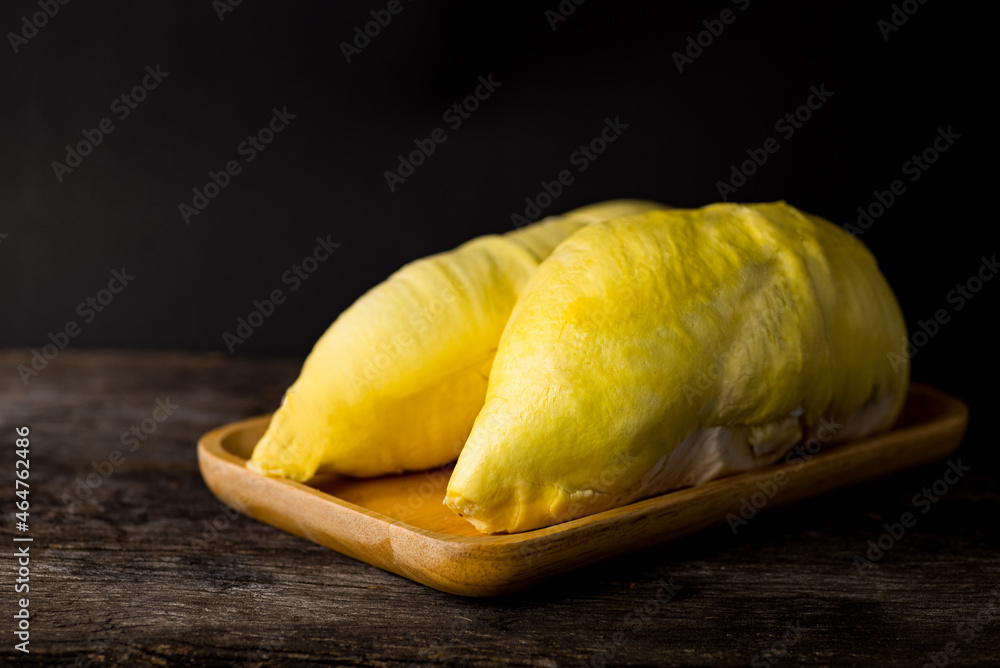 Durian with two golden ripe meat on the wooden tray with a dark and ...