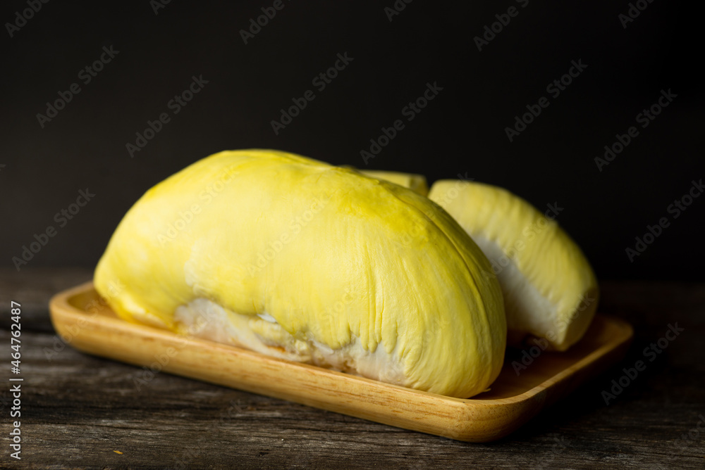 Durian with two golden ripe meat on the wooden tray with a dark and ...