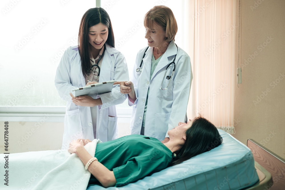 Caucasian senior woman doctor teach Asian medical student by bedside ...