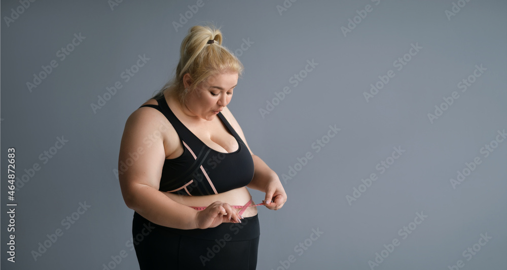 A plump female with a surprised face and open mouth measures the size ...