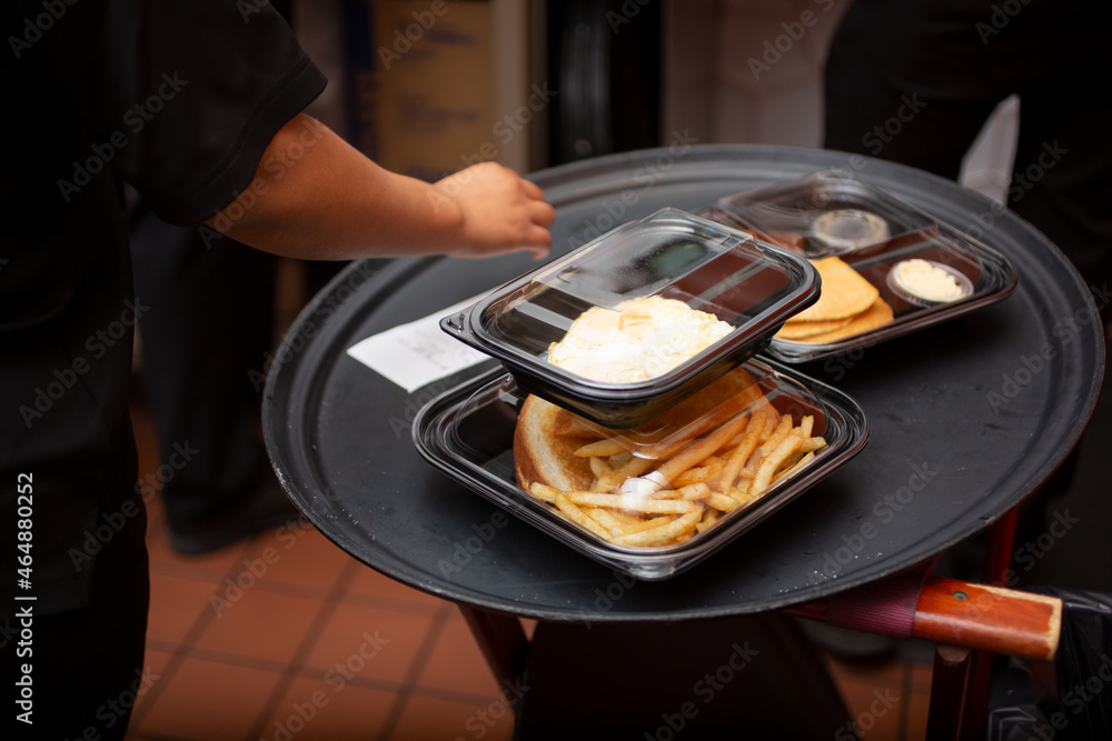 A view of an employee attending to a tray full of to-go containers, in ...