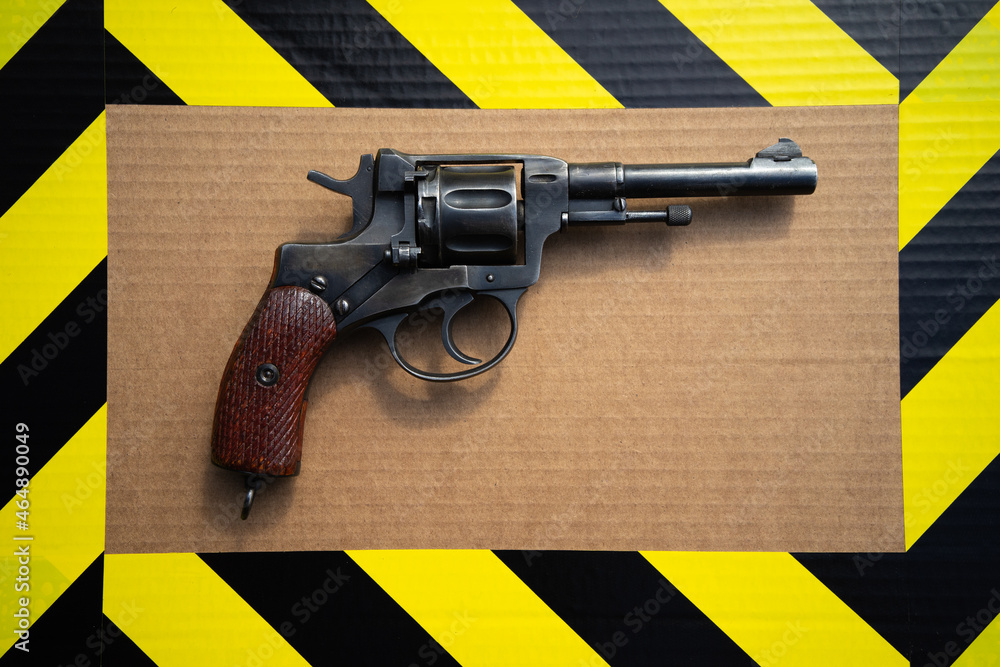 A metal revolver of the nagant system on a cardboard background. There ...