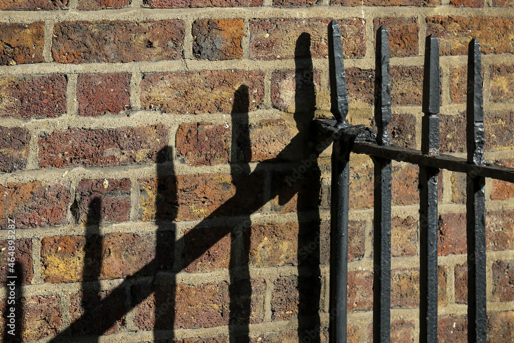 Black iron railings cast linear shadows or lines onto old stone brick ...
