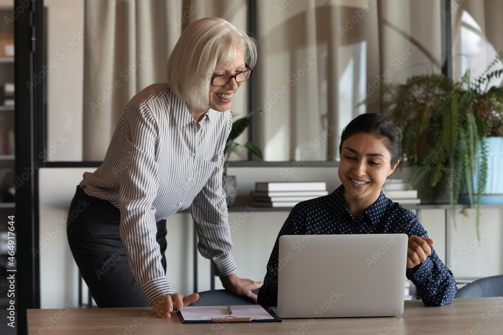 Stockfoto Friendly elderly female boss supervise work of young mixed ...