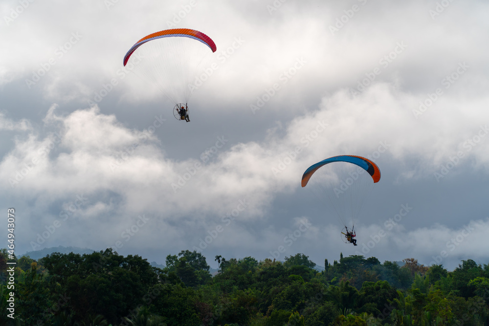 Paramotor gliding and flying in the air with majestic clouds are ...