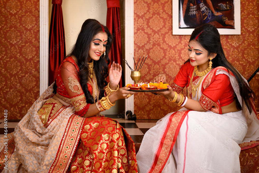 Two Indian women, dressed in traditional sarees and lehengas with gold ...