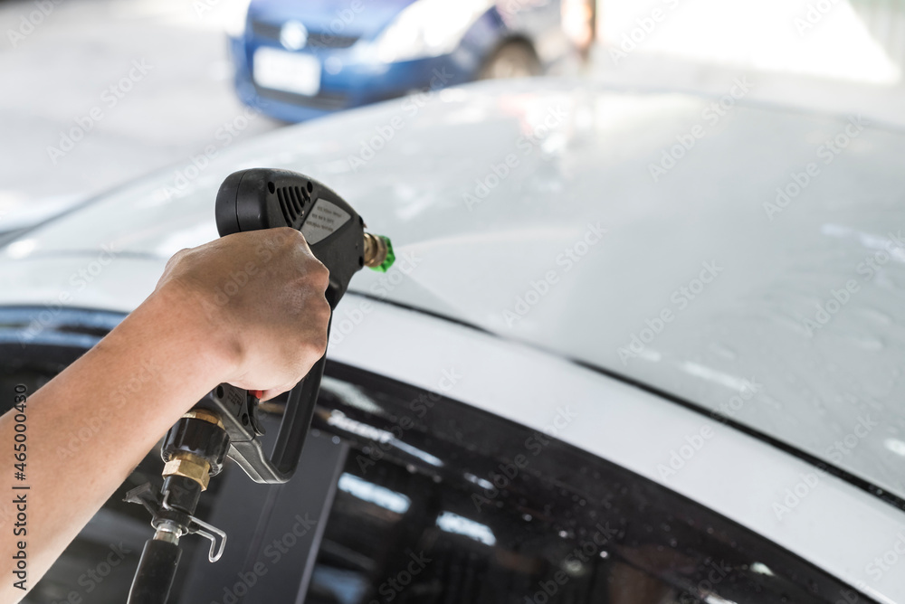 Washing the roof of the car with a high pressure water spray gun. At a ...