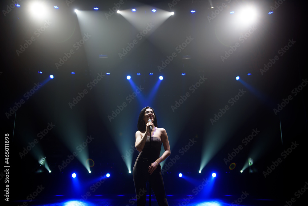 Singer perform on stage of nightclub in front of bright screen. Dark ...