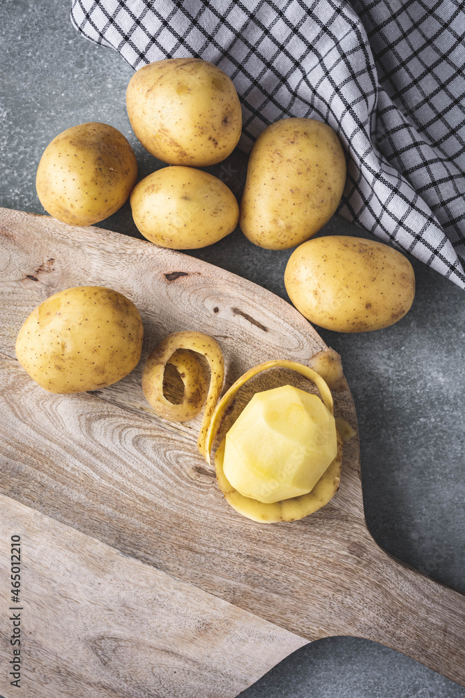 vista superior de una patata pelada y varias patatas enteras sobre una ...
