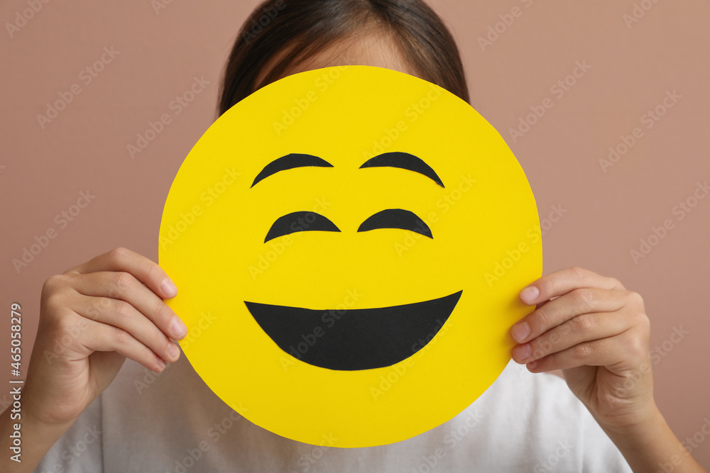 Little girl covering face with laughing emoji on pale pink background ...