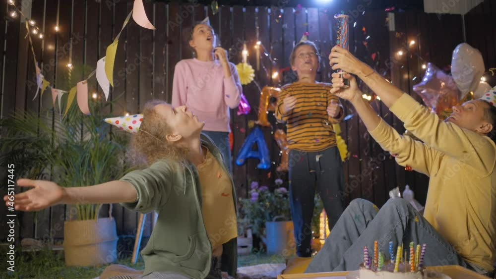 Father uses party popper and happy children with mother catch shiny ...