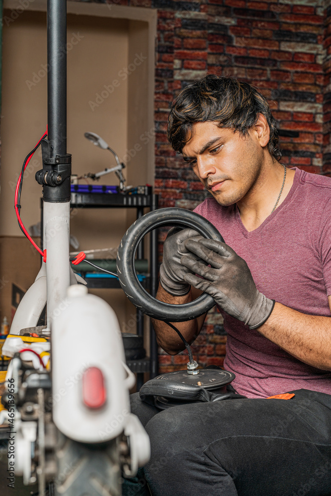 Mechanic repairing an electric scooter sitting on chair holding the ...
