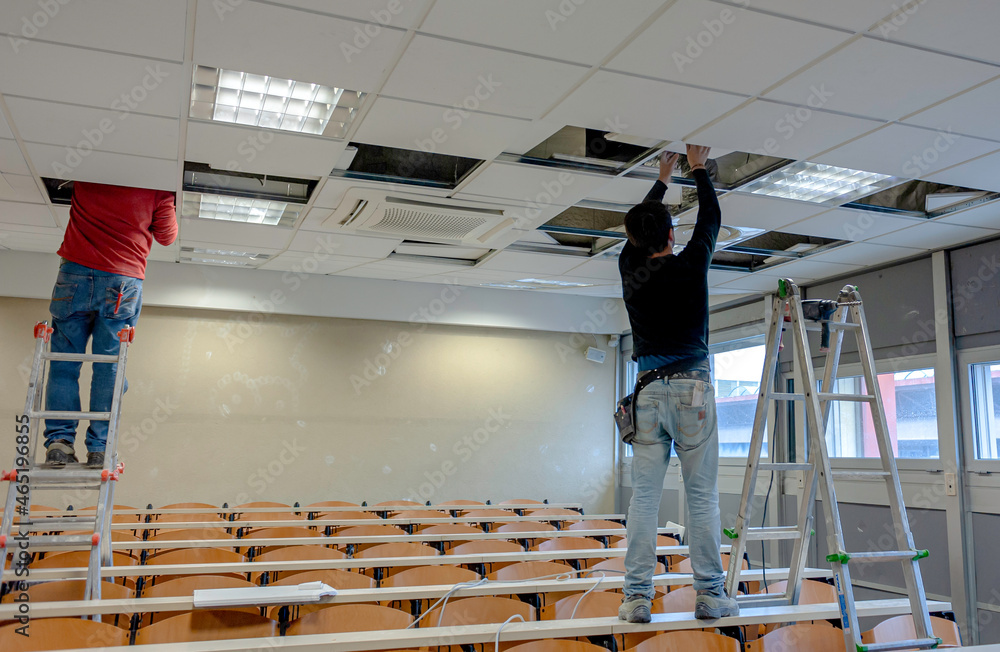 Construction worker assemble a suspended ceiling with drywall and ...