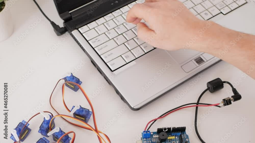 A male programmer creates robotics, an arduino board controls servo ...