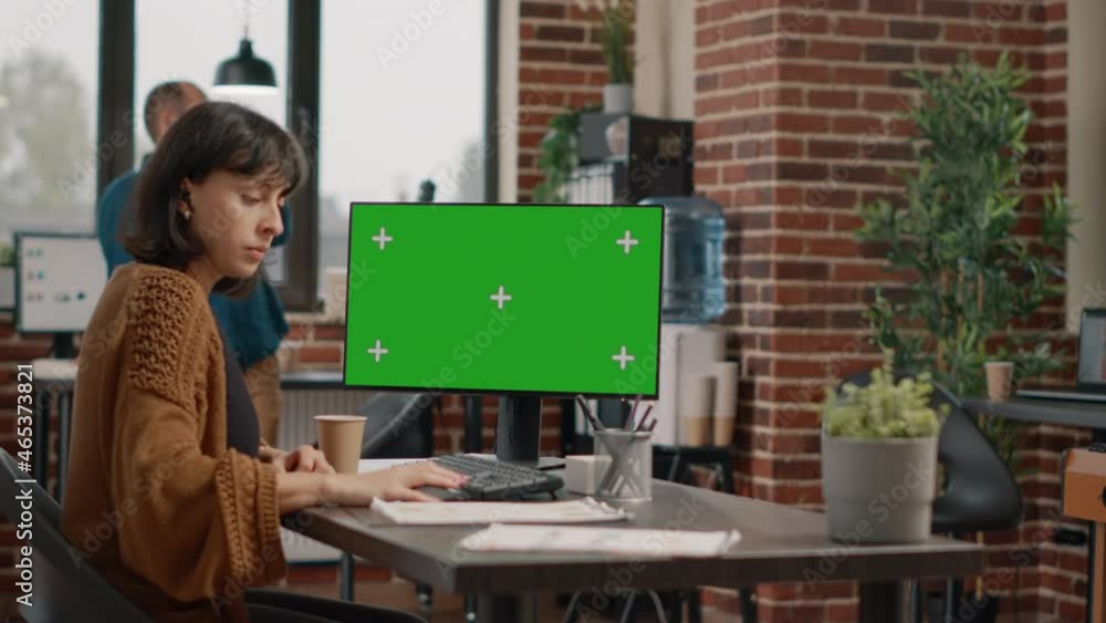 Employee looking at horizontal green screen on computer display at desk ...