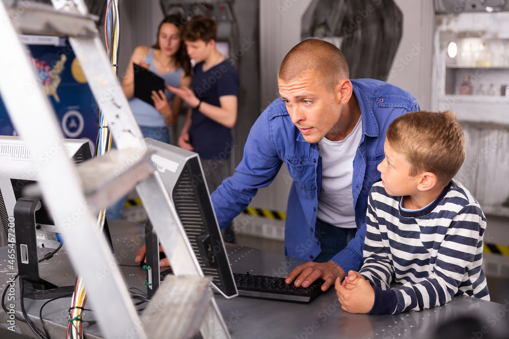 Interested young man with his tween son using computer to find solution ...