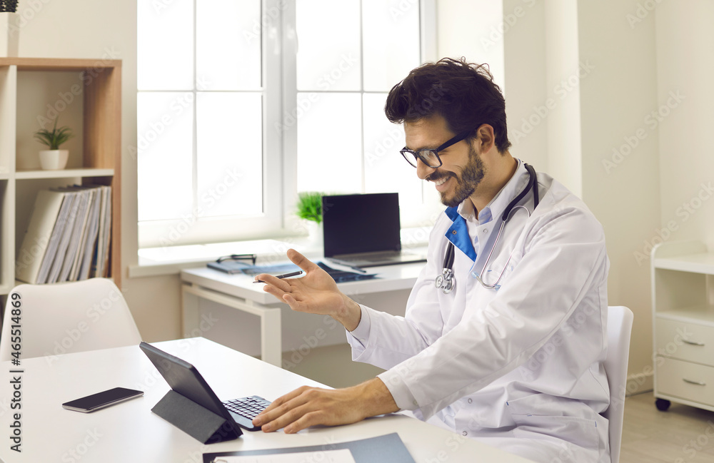 Happy young online doctor looking at computer screen and communicating ...
