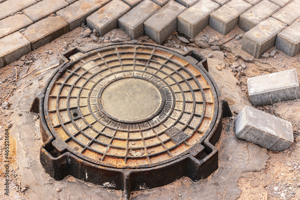 Installation of a heavy cast iron sewer manhole on a well before paving ...