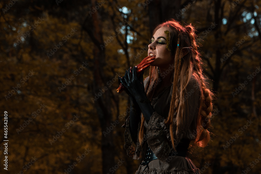 girl in dreadlocks and an old witch costume eats a human hand, a model ...