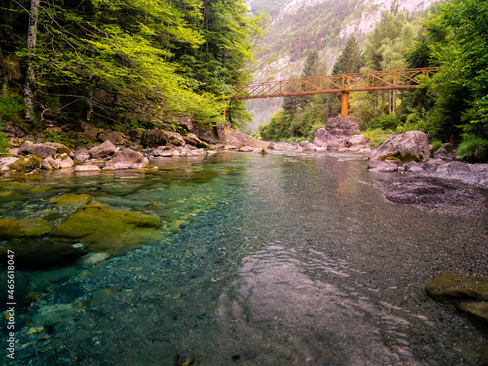 Paisaje montaña en el que un río transcurre entre árboles y rocas y ...