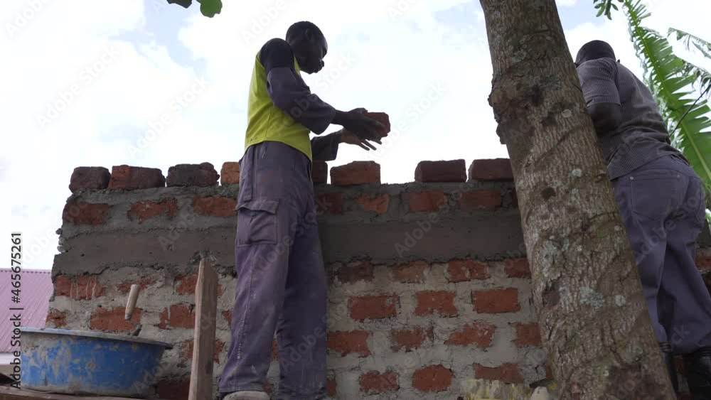 Two African people constructing a traditional house in Africa. Worker ...