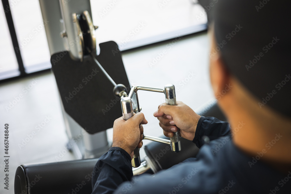 Young Fitness man pull up the machine bar in gym. Guy weight training ...