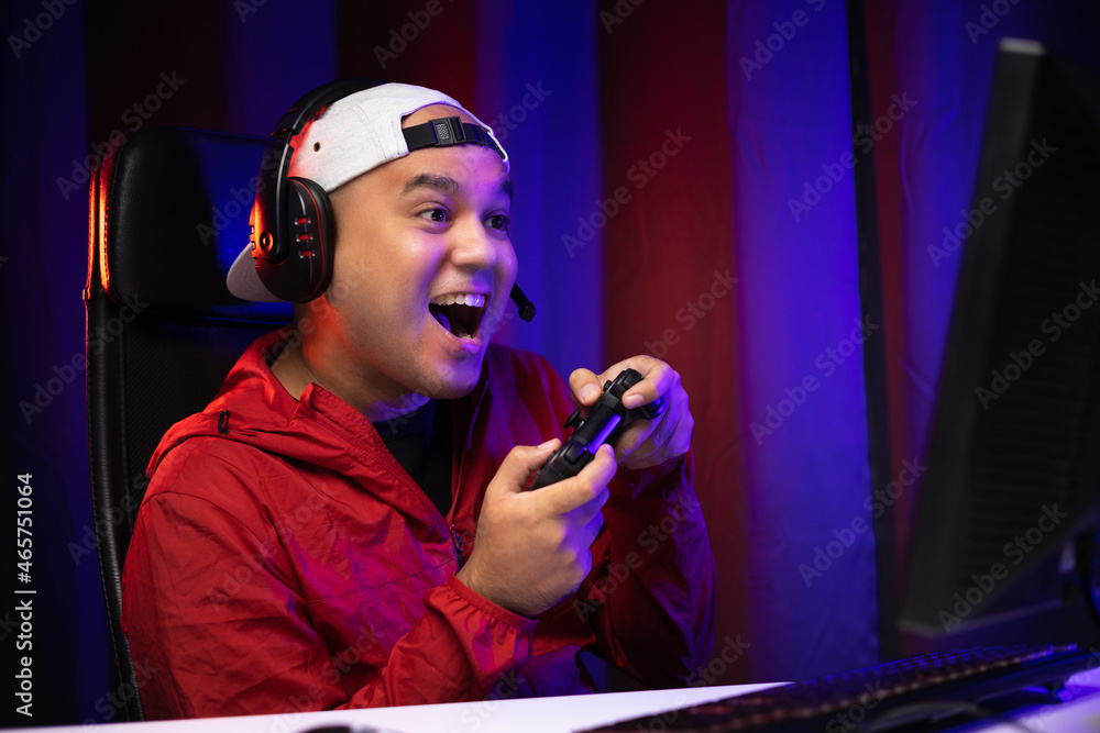Foto de Excited and shocked face of Asian gamer with headphone holding ...