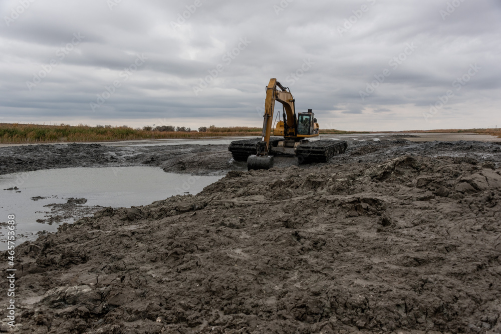 Amphibious water excavator clears the dried river bed channel from the ...