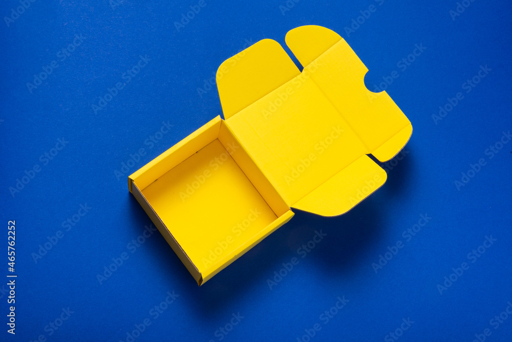 Simple yellow cardboard box on color background, empt inside, opened ...