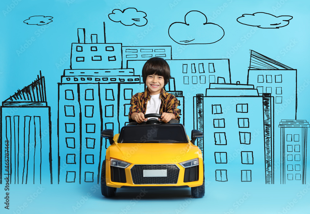 Cute little boy driving toy car and drawing of city on light blue ...