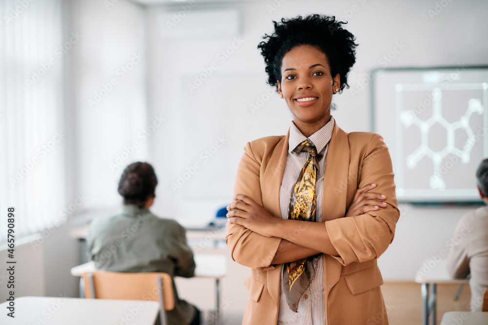Portrait of happy confident African American teacher in classroom looks ...