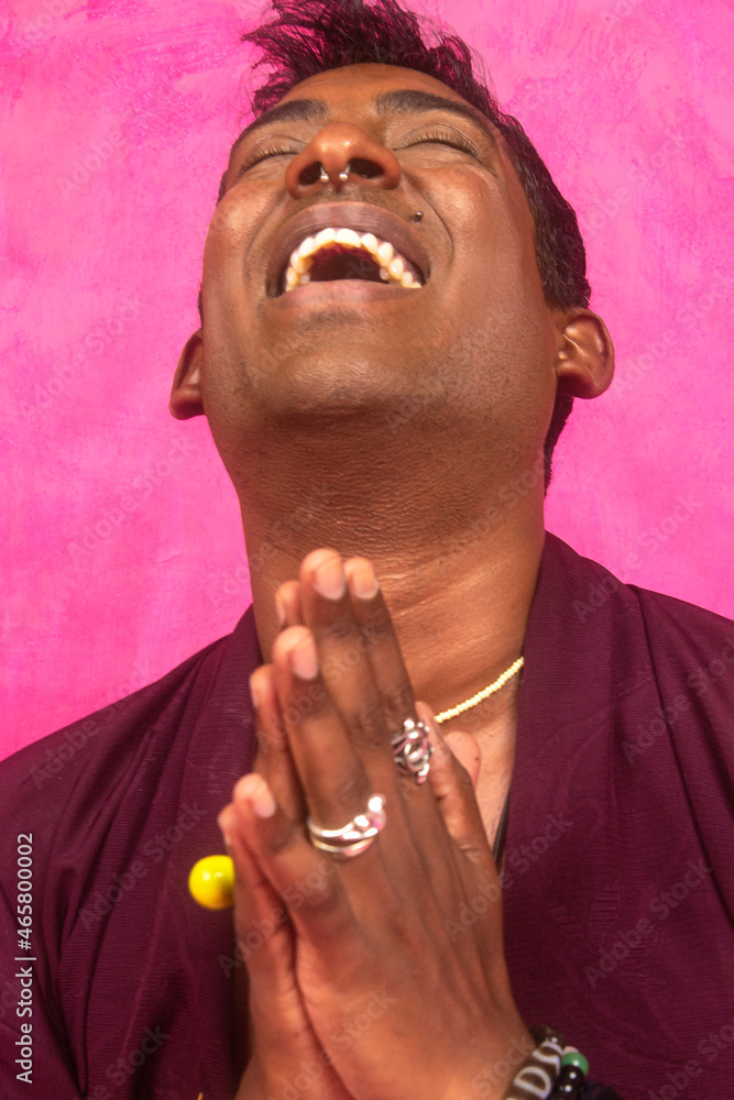 Malaysian Indian man laughing against a pink backdrop in a studio ...